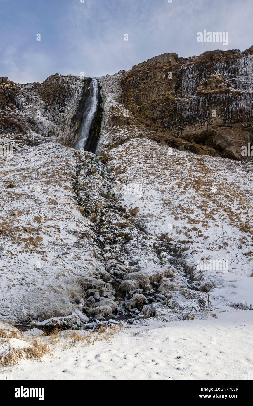 Small waterfall off rocky cliff with snow and ice, Seljalandsfoss area ...