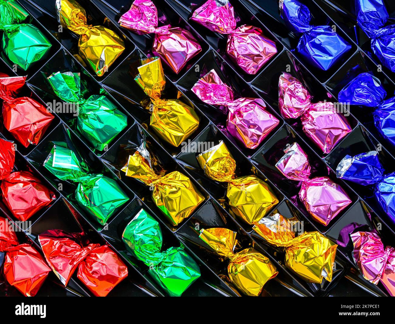 chocolate candies in shining wrapper of different colors in regular ...