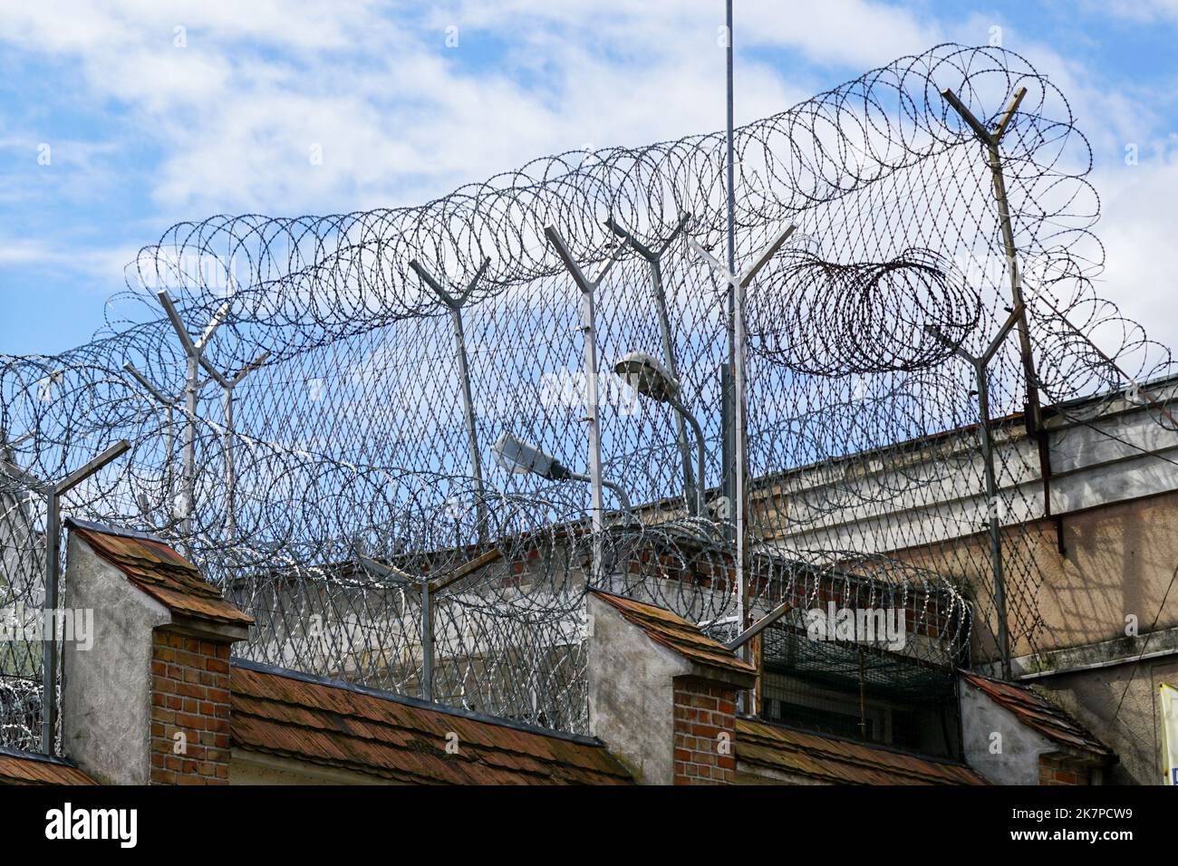 Lots of barbed wire over a brick fence around the perimeter of the ...