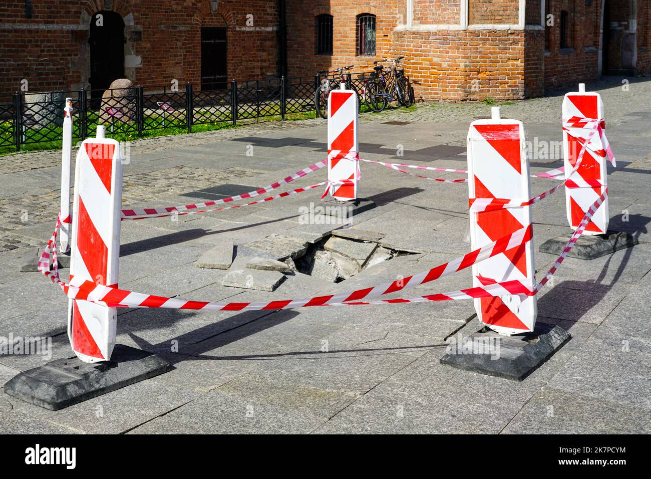 Collapse of pavement slabs on city street, restricted by red and white ...