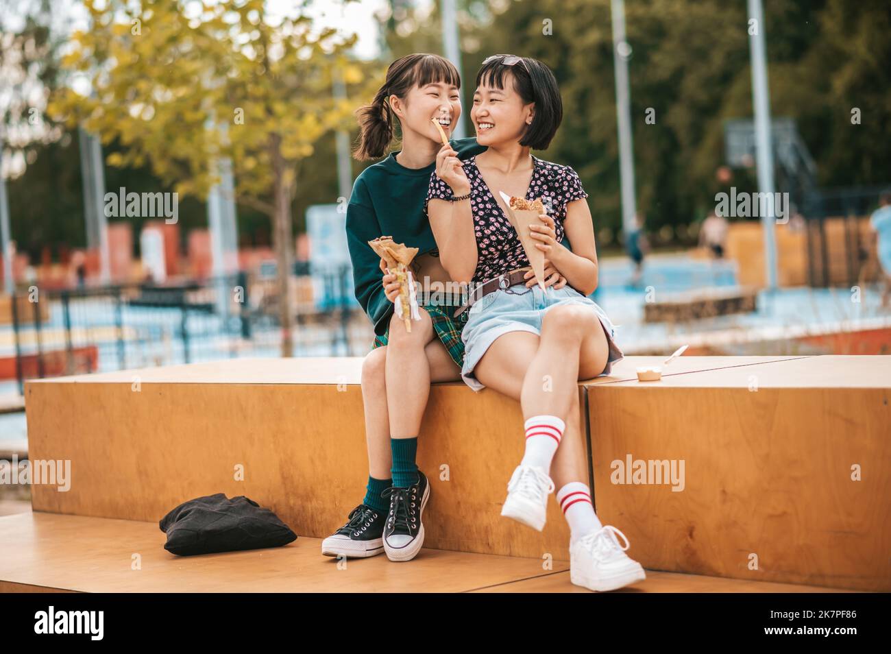 Enjoying street food. Two sweet girl eating outside and feeding each ...