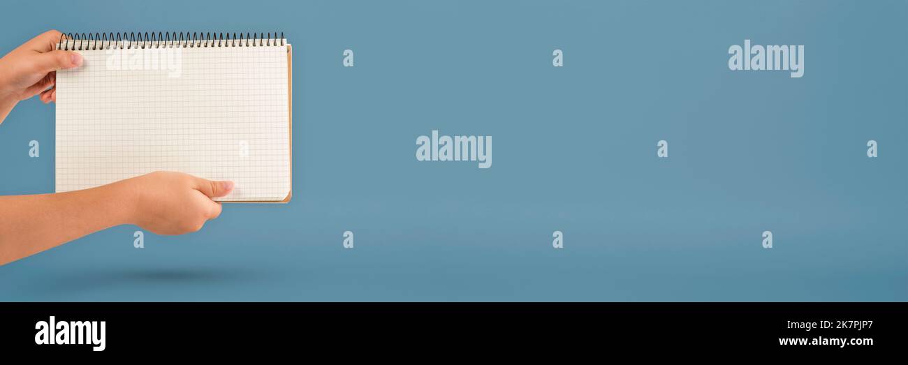 Notepad in hand. Blank notepad in the hands on a blue background. Hands ...