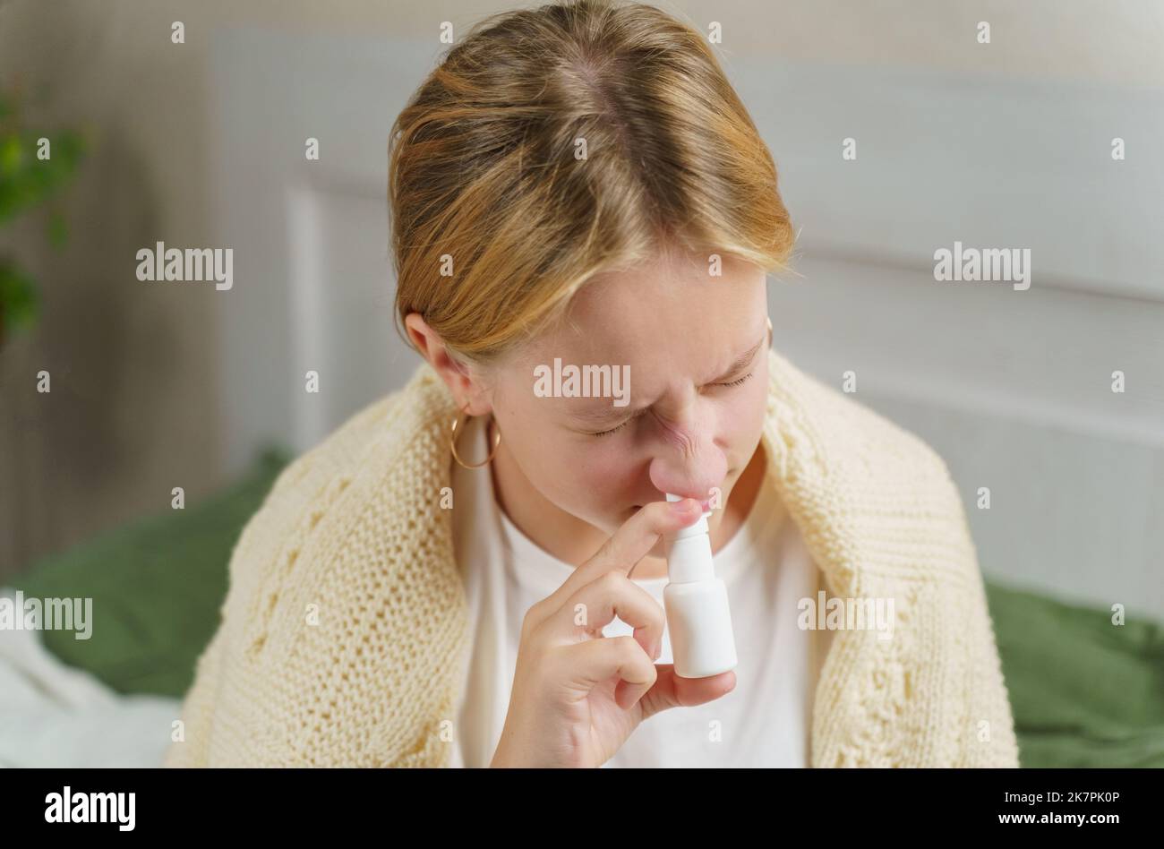 A girl with a cold treats a runny nose with a nasal spray. Medicine and ...