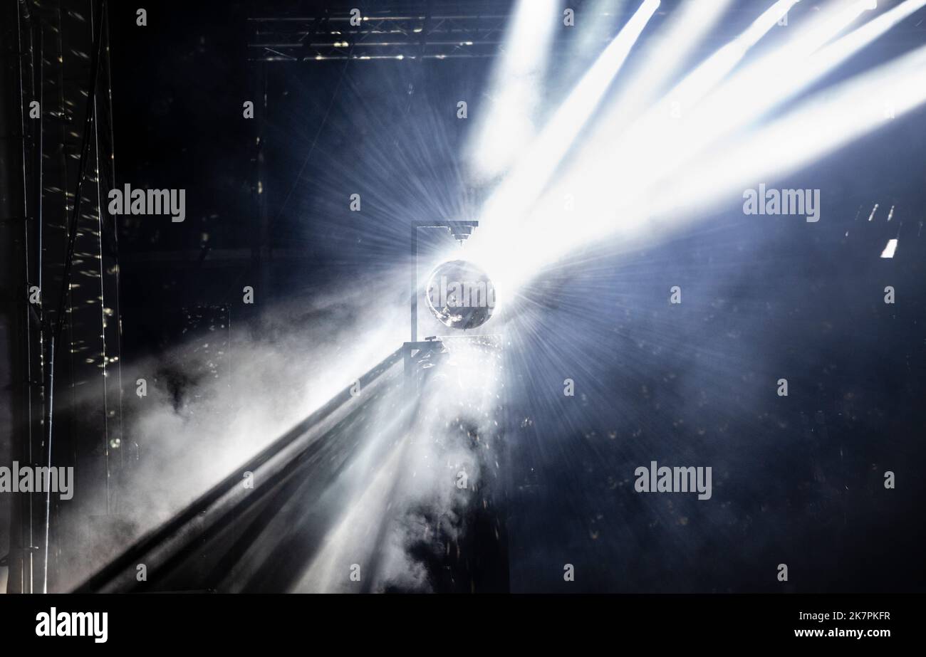 Disco ball with spotlights of white light on a stage with a black ...