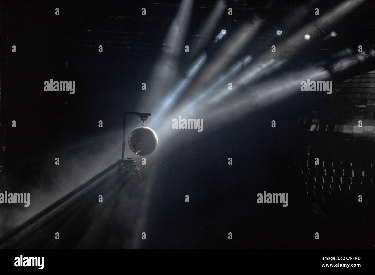 Disco ball with spotlights of white light on a stage with a black ...