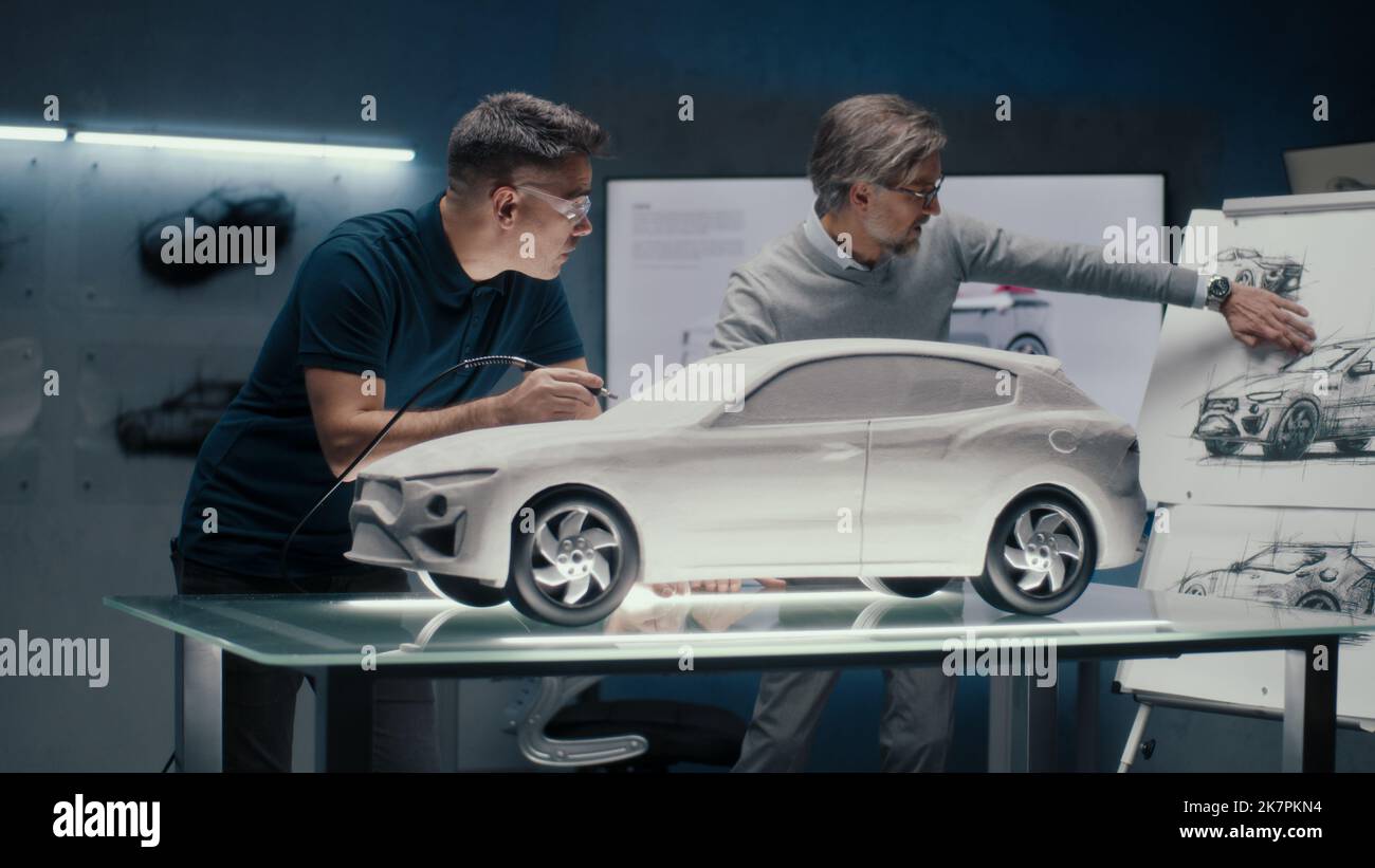 Two experienced automotive engineers discuss the car design looking at ...