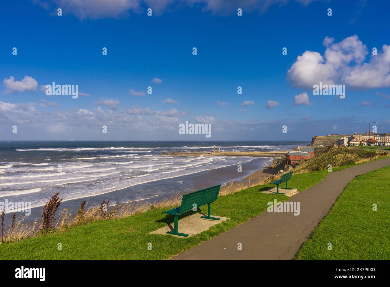 Seats on the clifftop path in Whitby, North Yorkshire. The view is of ...