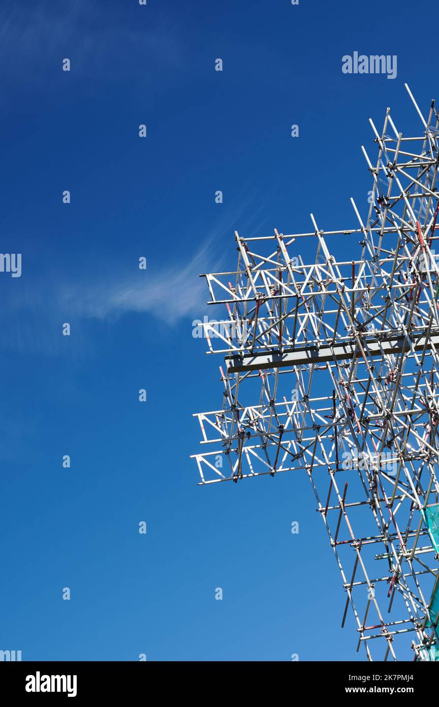 looking up at metal scaffolding at construction site with blue sky ...
