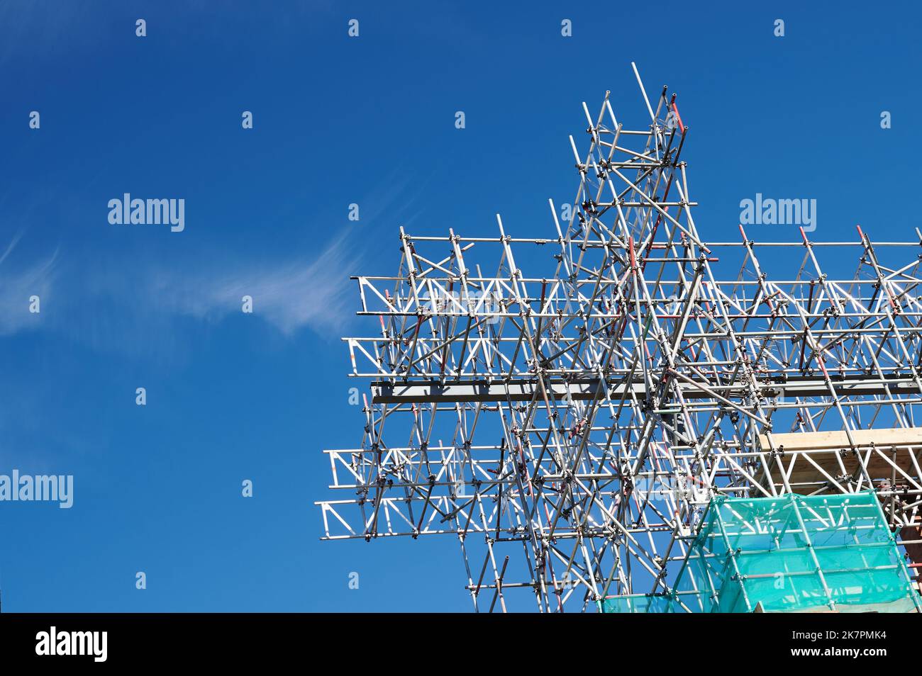 looking up at metal scaffolding at construction site with blue sky ...