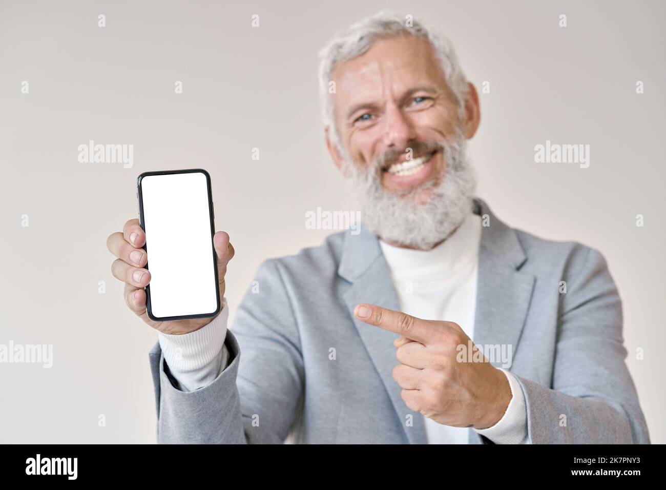 Older business man pointing at phone with white mock up screen isolated ...