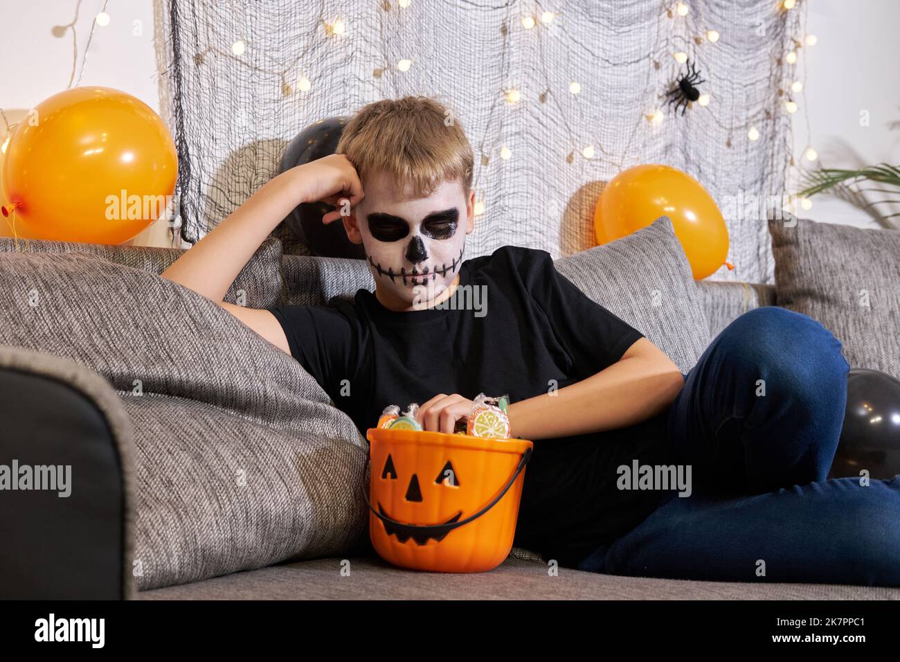 A boy in skeleton makeup pulls out candy from a Halloween party Stock ...