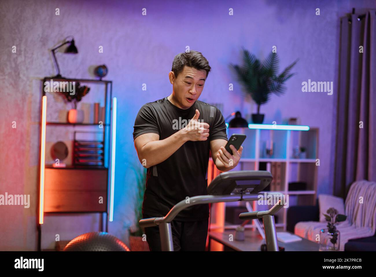 Side view of young confident handsome asian man looking at smartphone ...