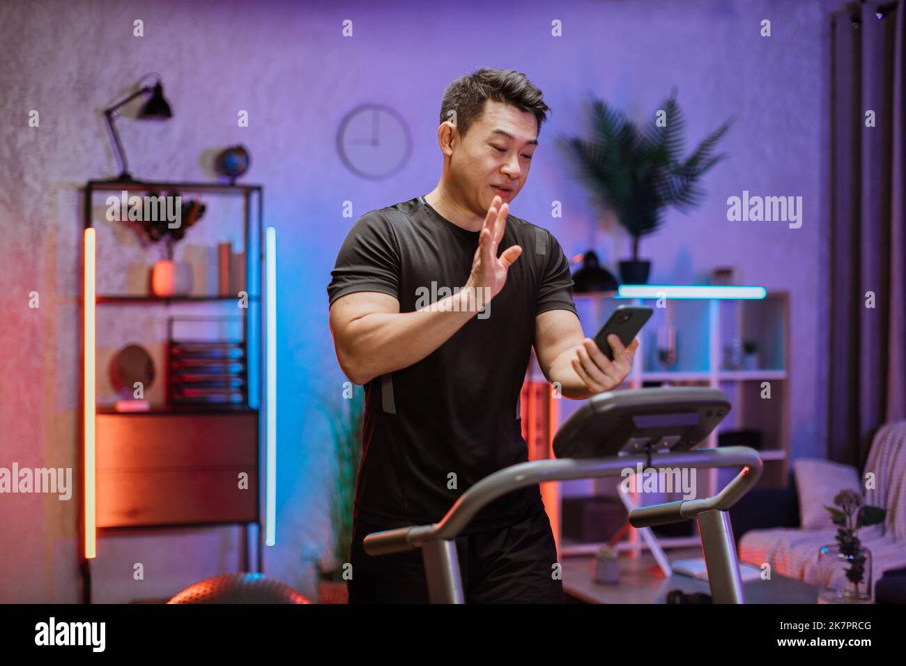 Side view of young confident handsome asian man looking at smartphone ...