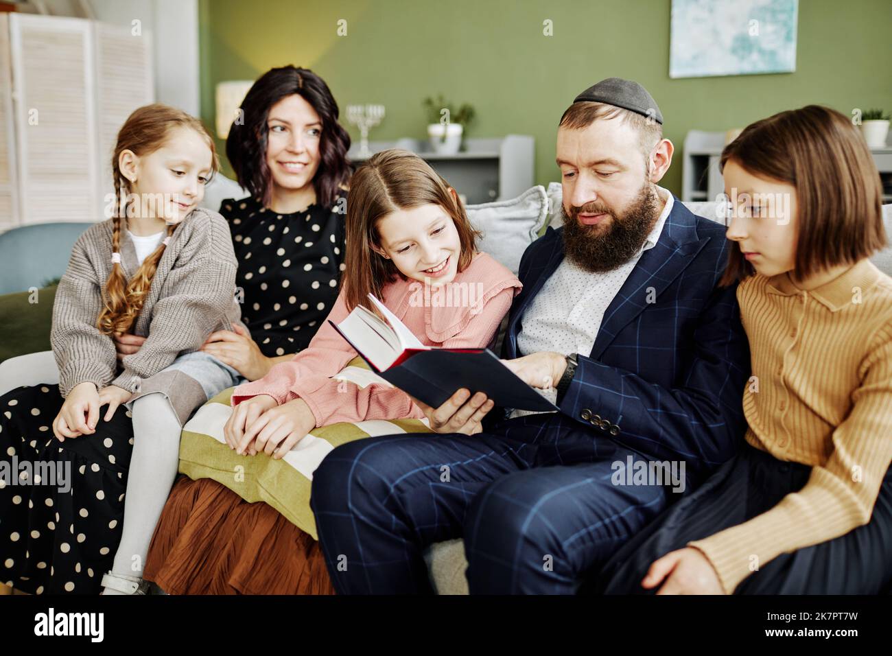 Portrait of orthodox Jewish man wearing kippah while reading book to ...