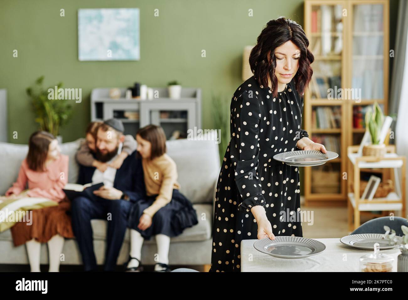 Portrait of Jewish family at home with focus on young woman setting ...