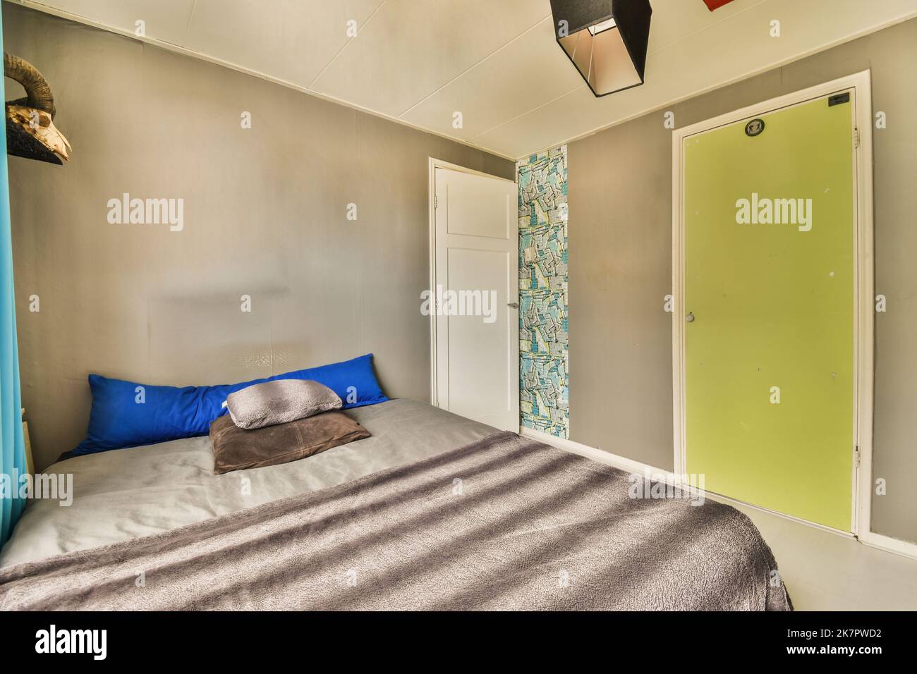 Comfortable bed covered with checkered blanket and located in light ...