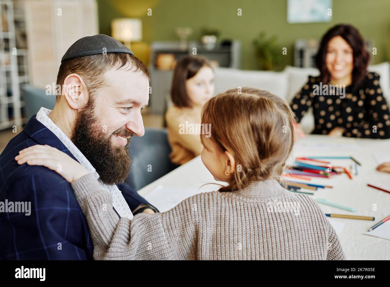 Side view portrait of smiling jewish man playing with children at home ...