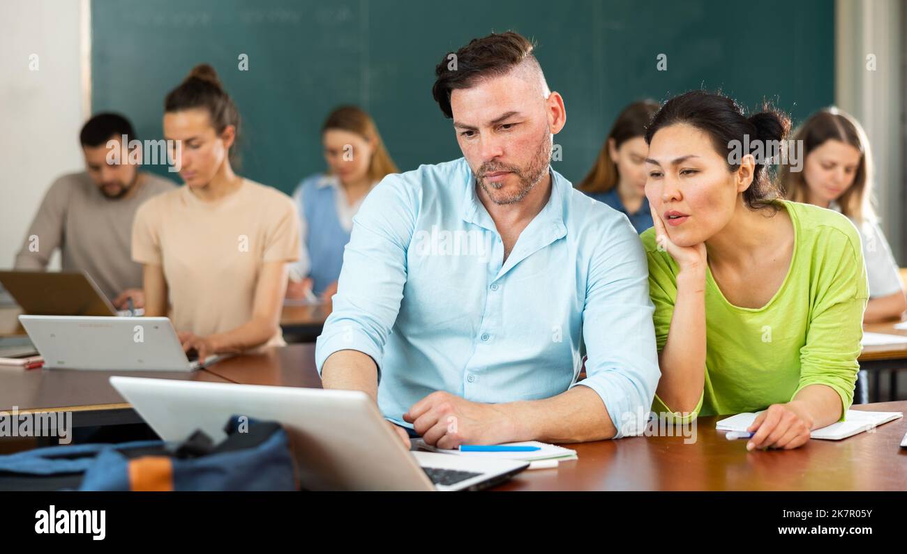 Group of adult students sitting at tables in classroom Stock Photo - Alamy