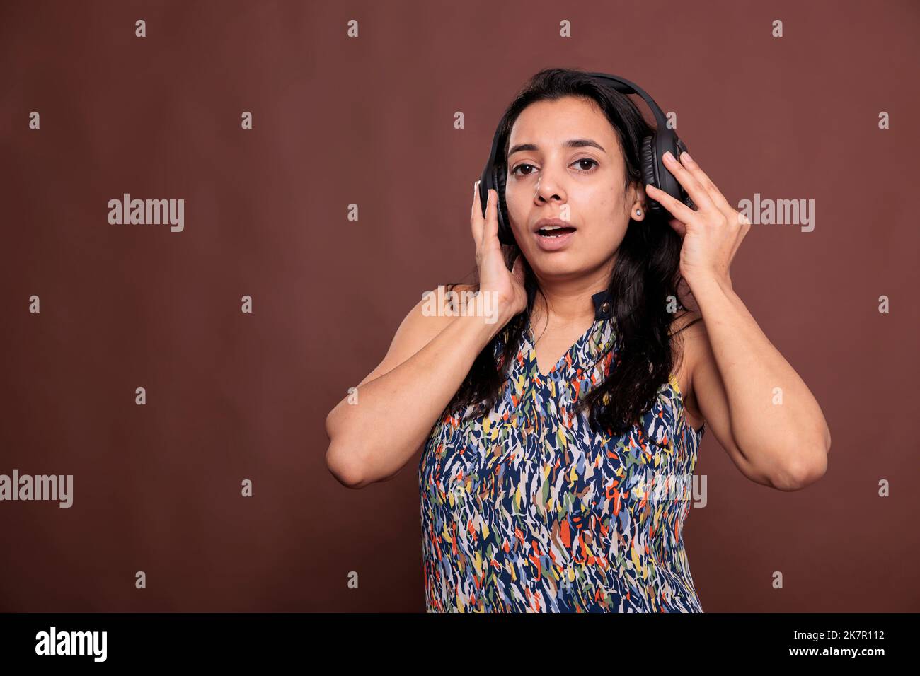Attractive woman taking off wireless headphones, looking at camera ...