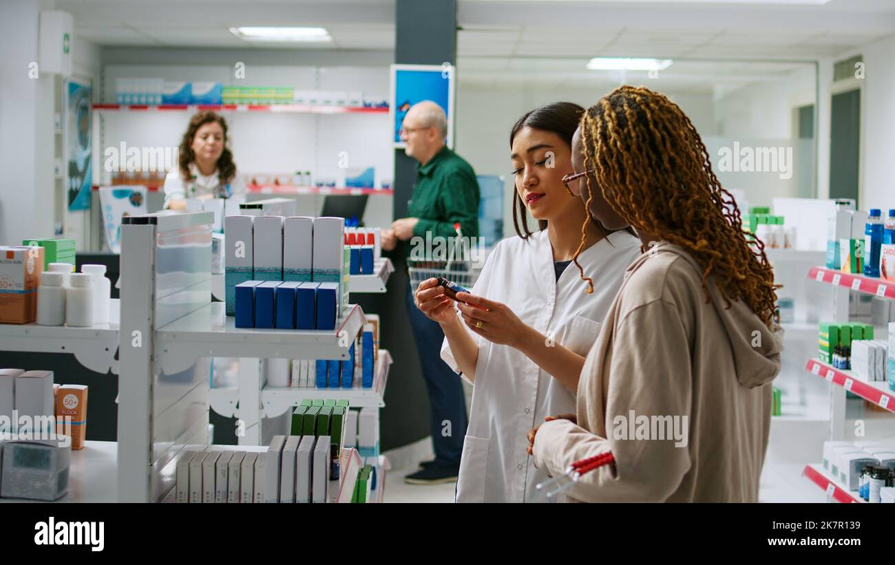 Medical employee helping multiethnic group of clients to buy ...