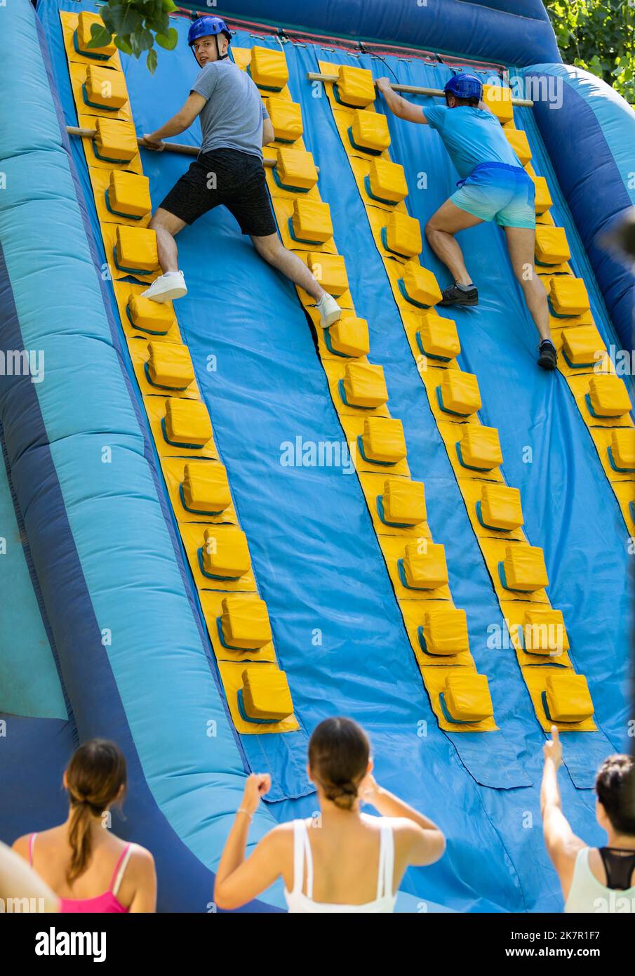 Two men climbing on inflatable castle with wooden sticks Stock Photo ...