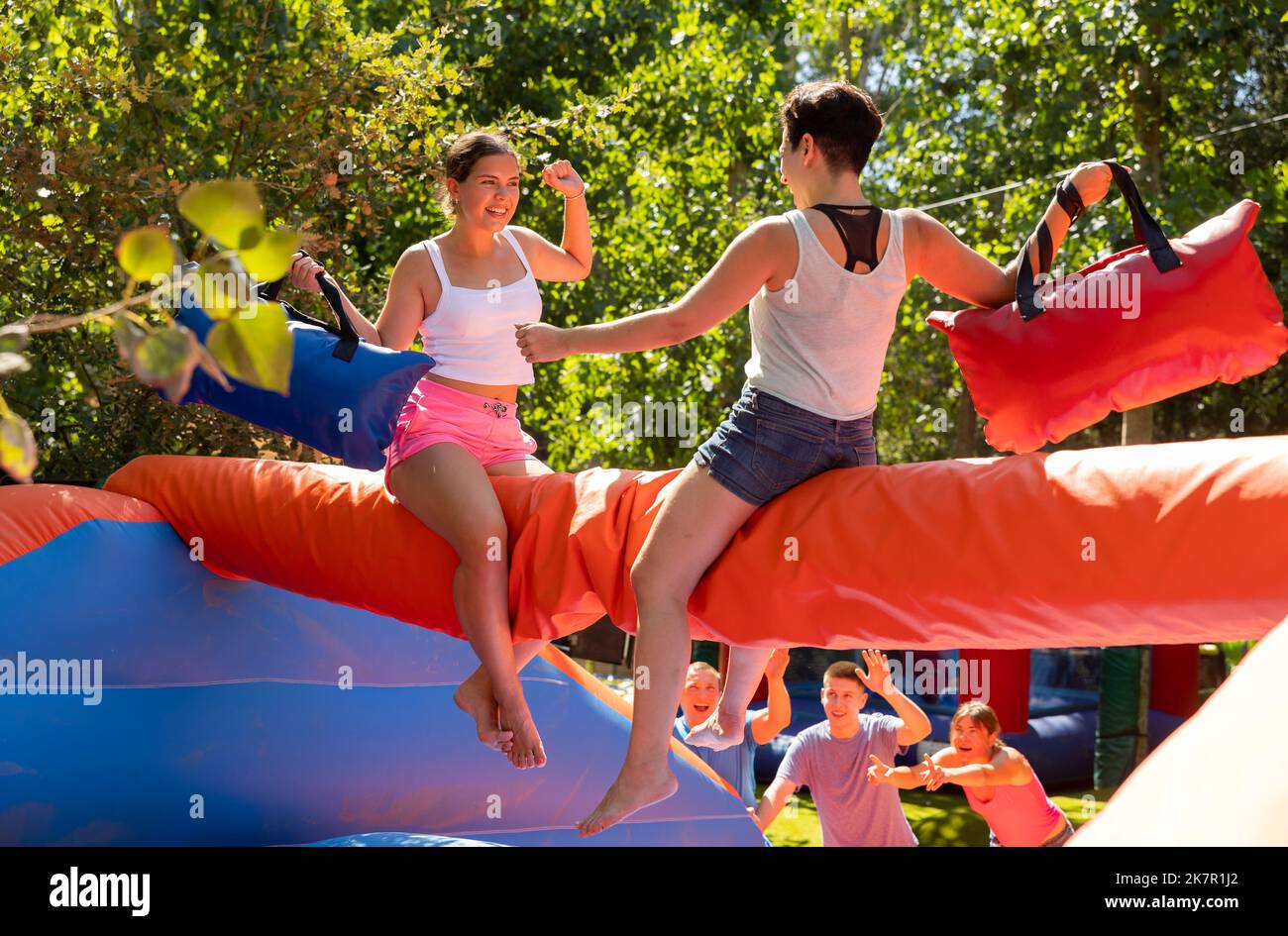 Laughing young girl fighting by pillows with female opponent on ...