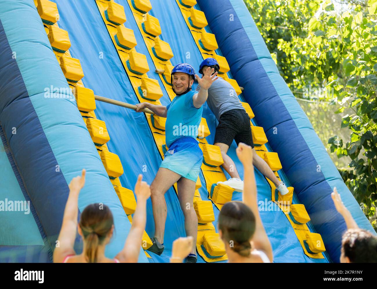 Men using sticks to reach top of slide in adventure park Stock Photo ...
