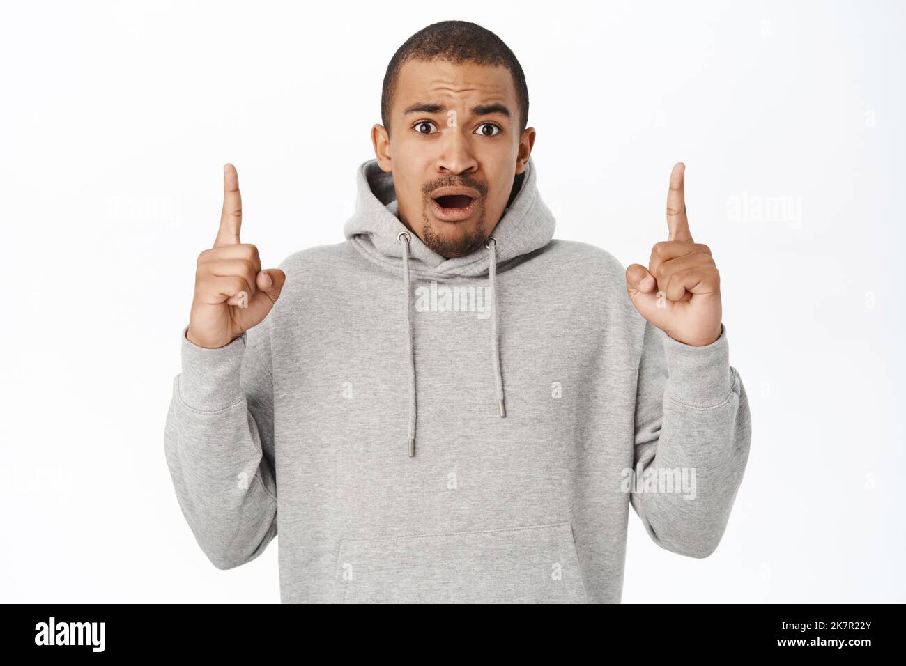 Shocked and worried guy pointing fingers up, looking alarmed and ...