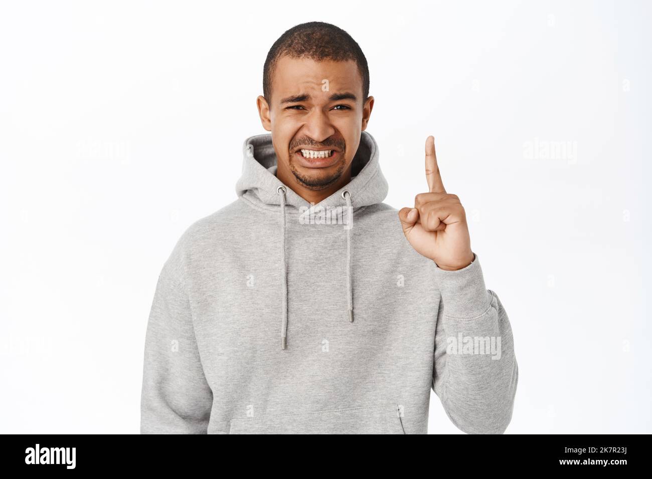 Yikes. Guy points up and squinting face, smth painful or sour, stands ...