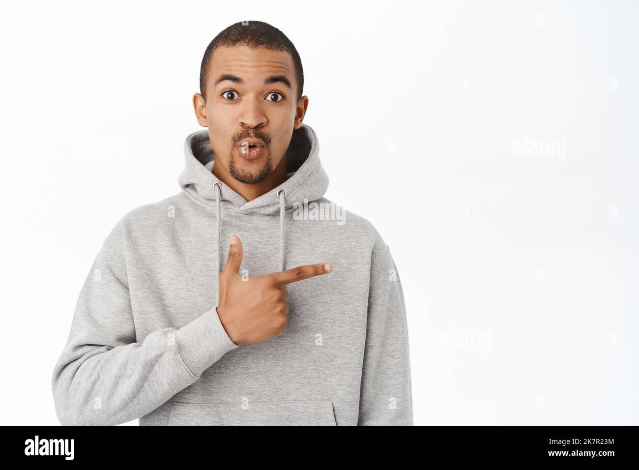 Portrait of surprised handsome guy points right, shows banner or logo ...