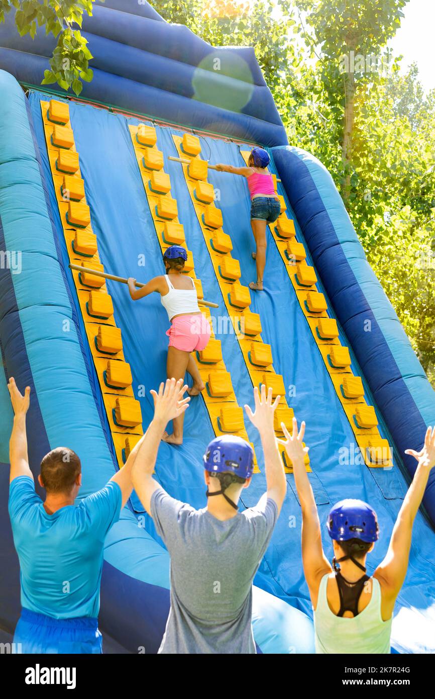 Two young women climbing on inflatable castle with wooden sticks Stock ...