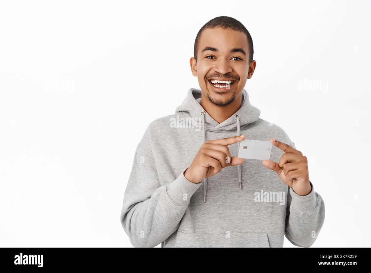Portrait of happy young man receives his banking card, showing credit ...