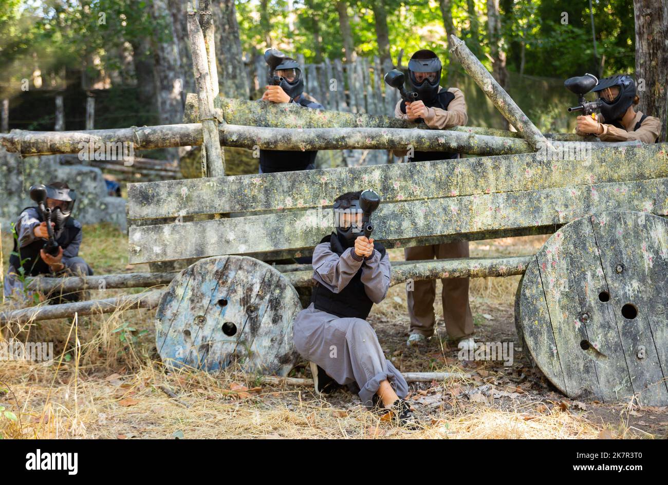 Group of people in full gear playing paintball on shooting range ...