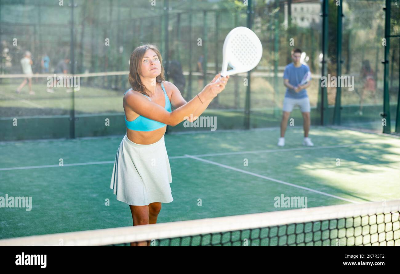 Young woman hitting two handed backhand during paddle tennis match ...