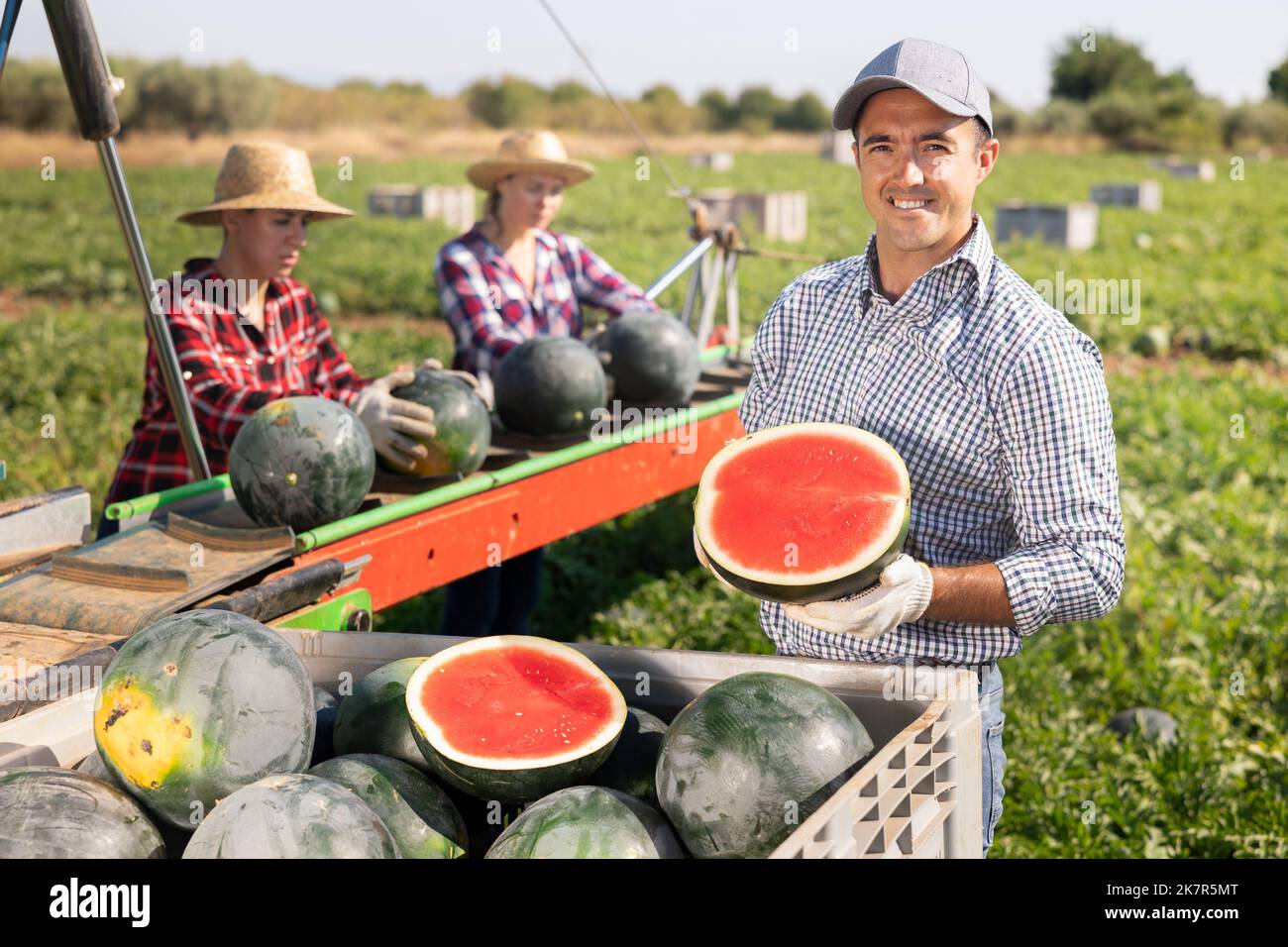 Portrait of positive male farmer with watermelon in his hands against ...