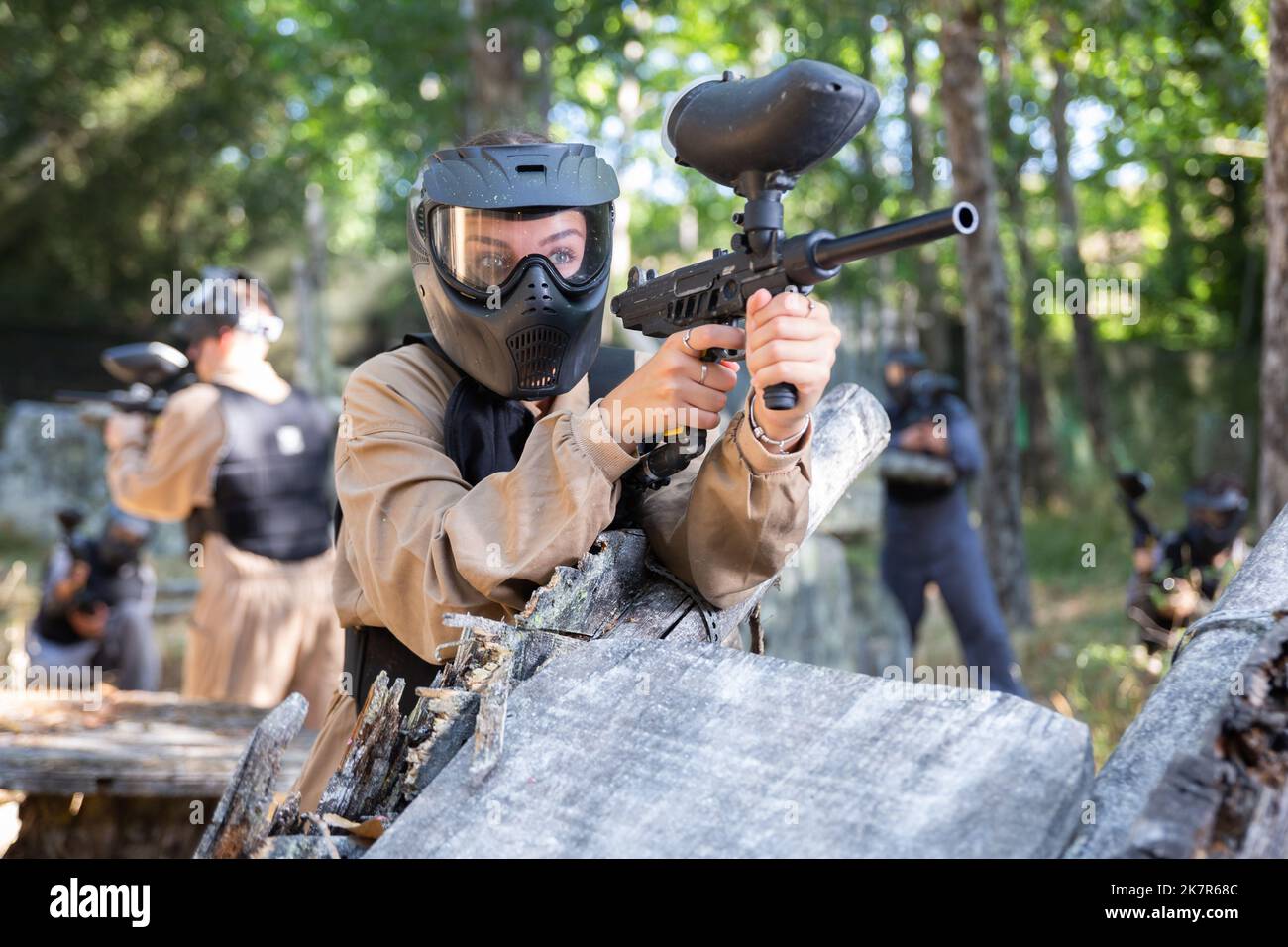 Young woman paintball player shooting with paintball marker Stock Photo ...