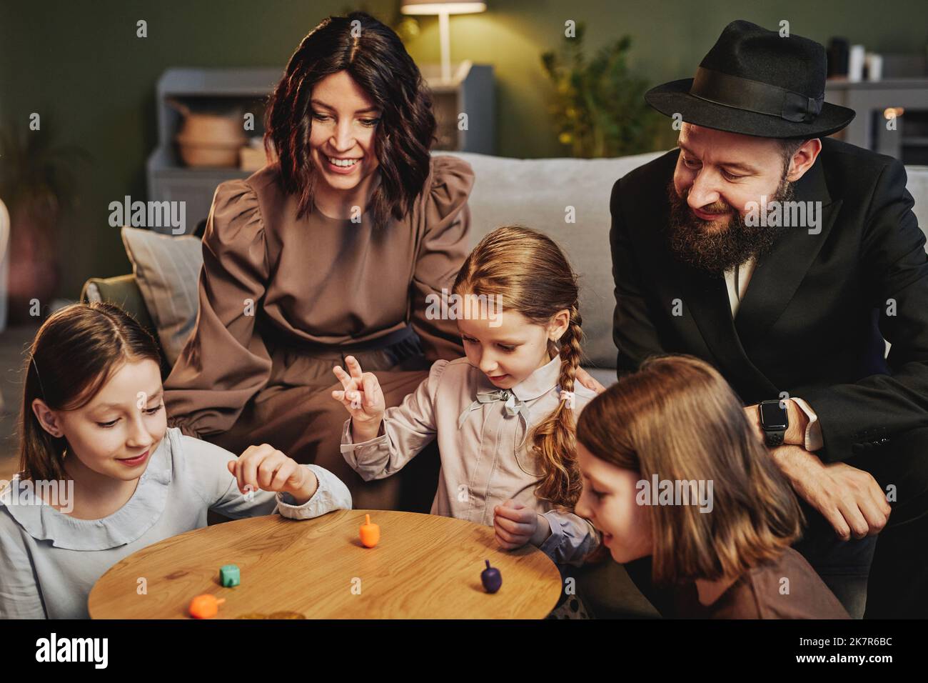 High angle view at modern jewish family playing traditional dreidel game in cozy home setting ...