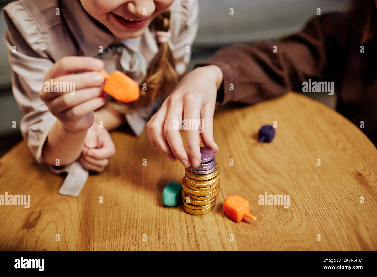 Close up of children stacking chocolate coins while playing jewish dreidel game, copy space ...