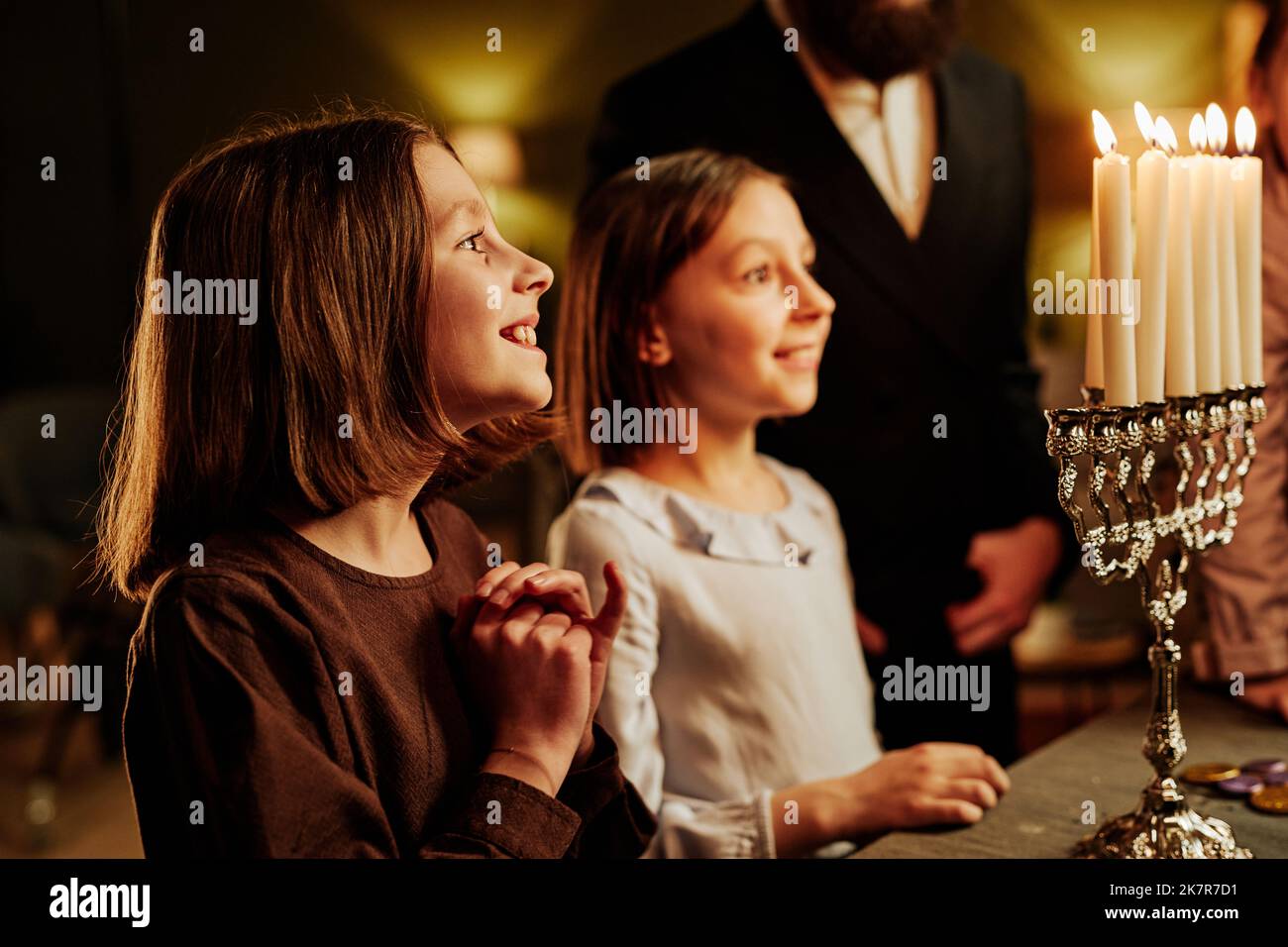 Side view portrait of smiling jewish girls looking at Menorah candle ...