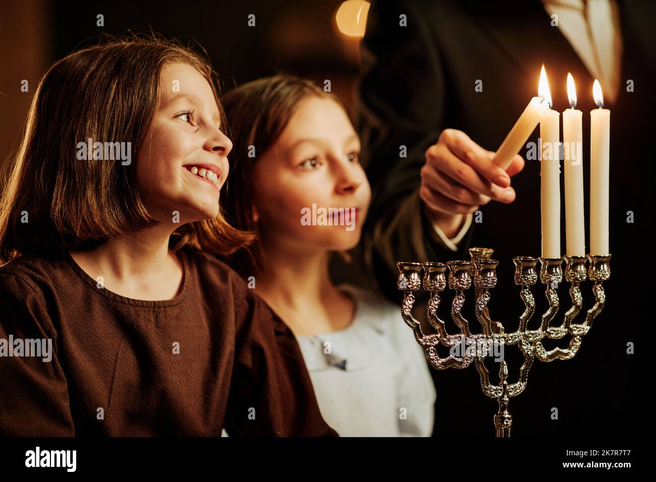 Side view portrait of two jewish girls looking at Menorah candle and ...