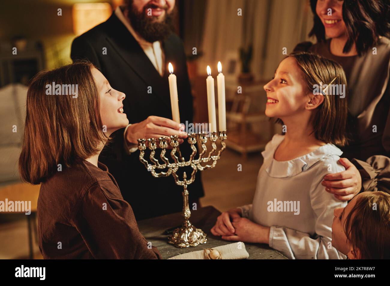 Portrait of orthodox jewish family lighting menorah candle together ...