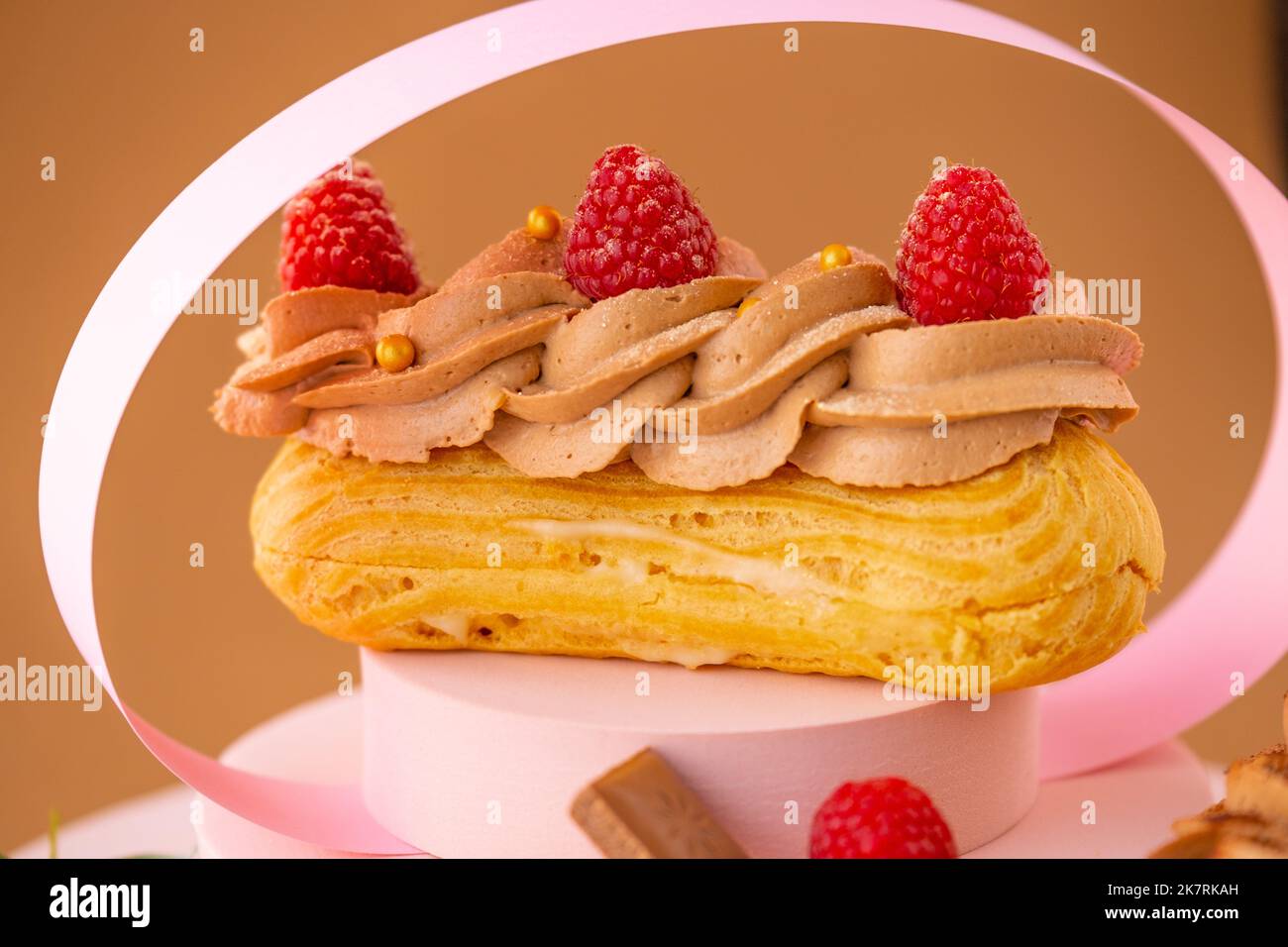 Eclairs cakes with cream and raspberries on a brown background. custard ...