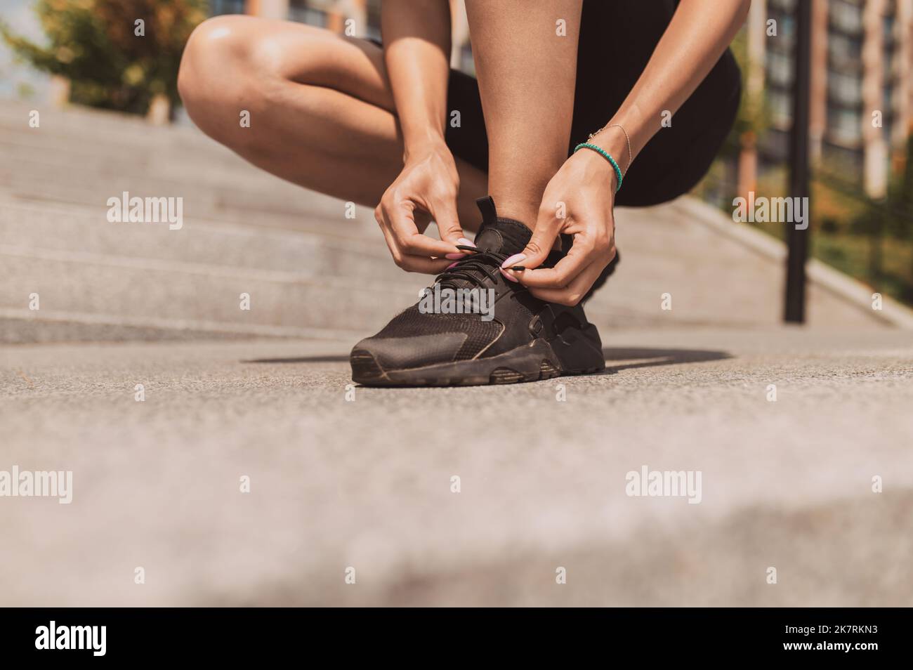 Curly-haired girl tying her sneakers during exercising Stock Photo - Alamy