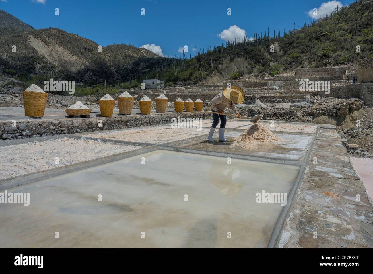 A man is working in the saline pools at a salt mining operation in ...