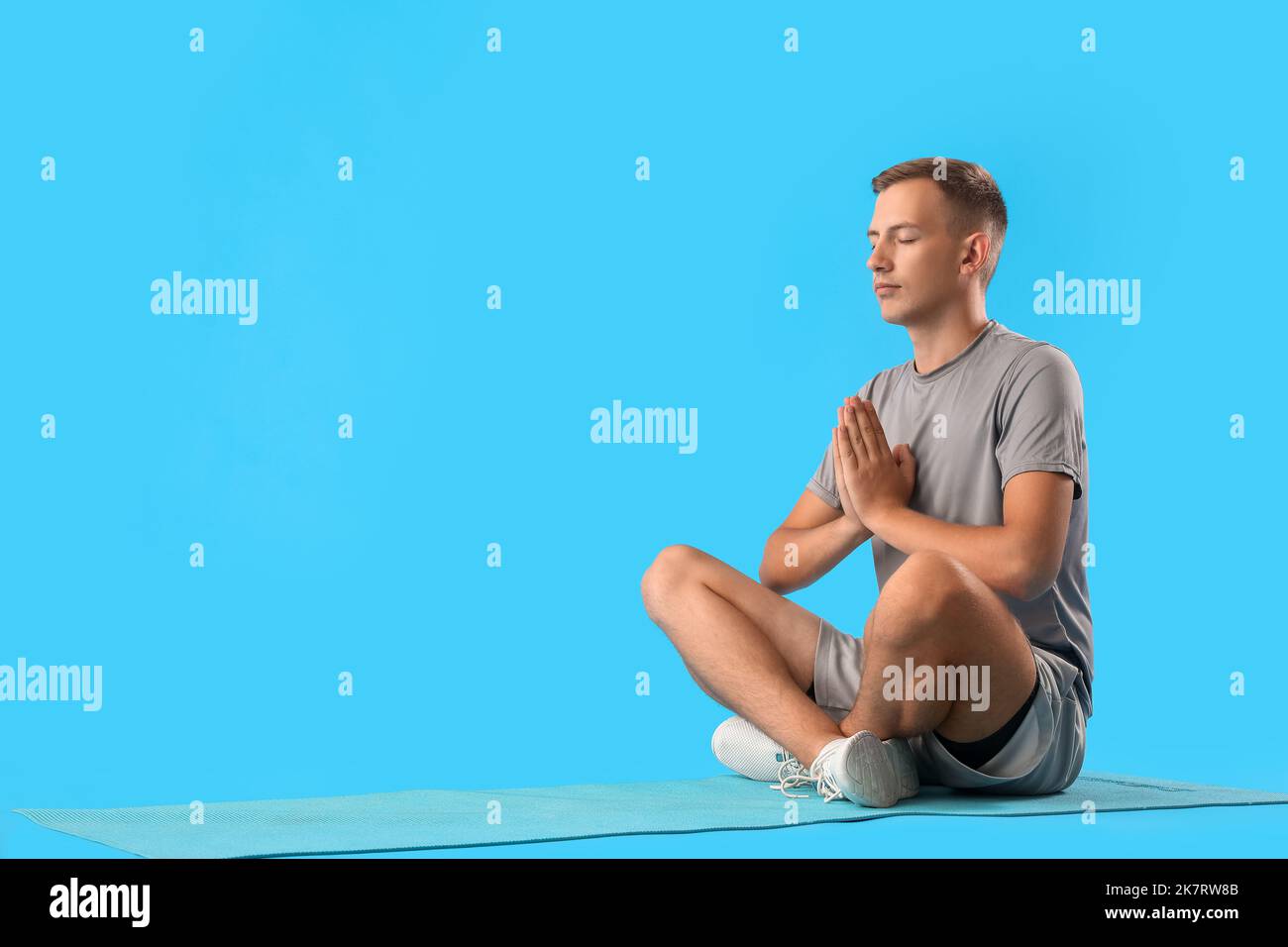 Sporty young man meditating on blue background Stock Photo - Alamy