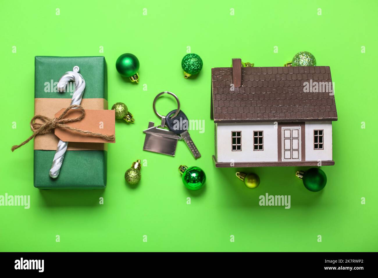 House model with key, gift and Christmas balls on green background ...