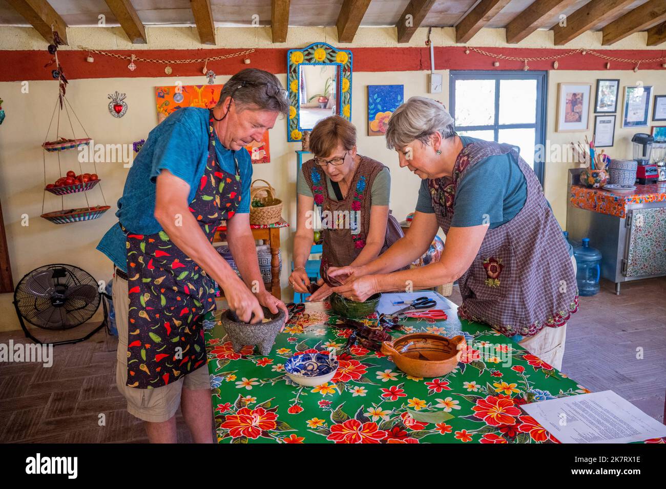 Tourists grinding the ingredients for making a red mole (a traditonal ...