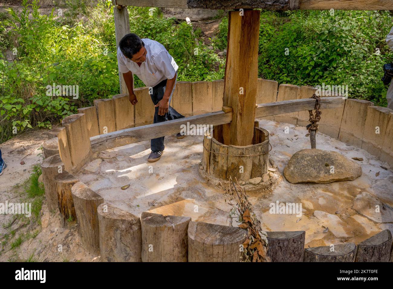 A man at an old water powered wheel used to crush rocks to extract the ...
