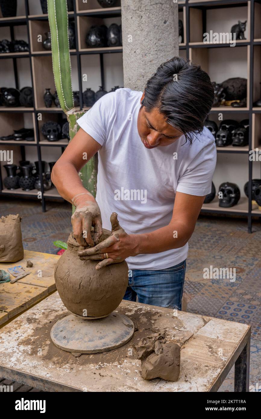 A potter is making a Barro negro pottery (black clay pottery) vase ...