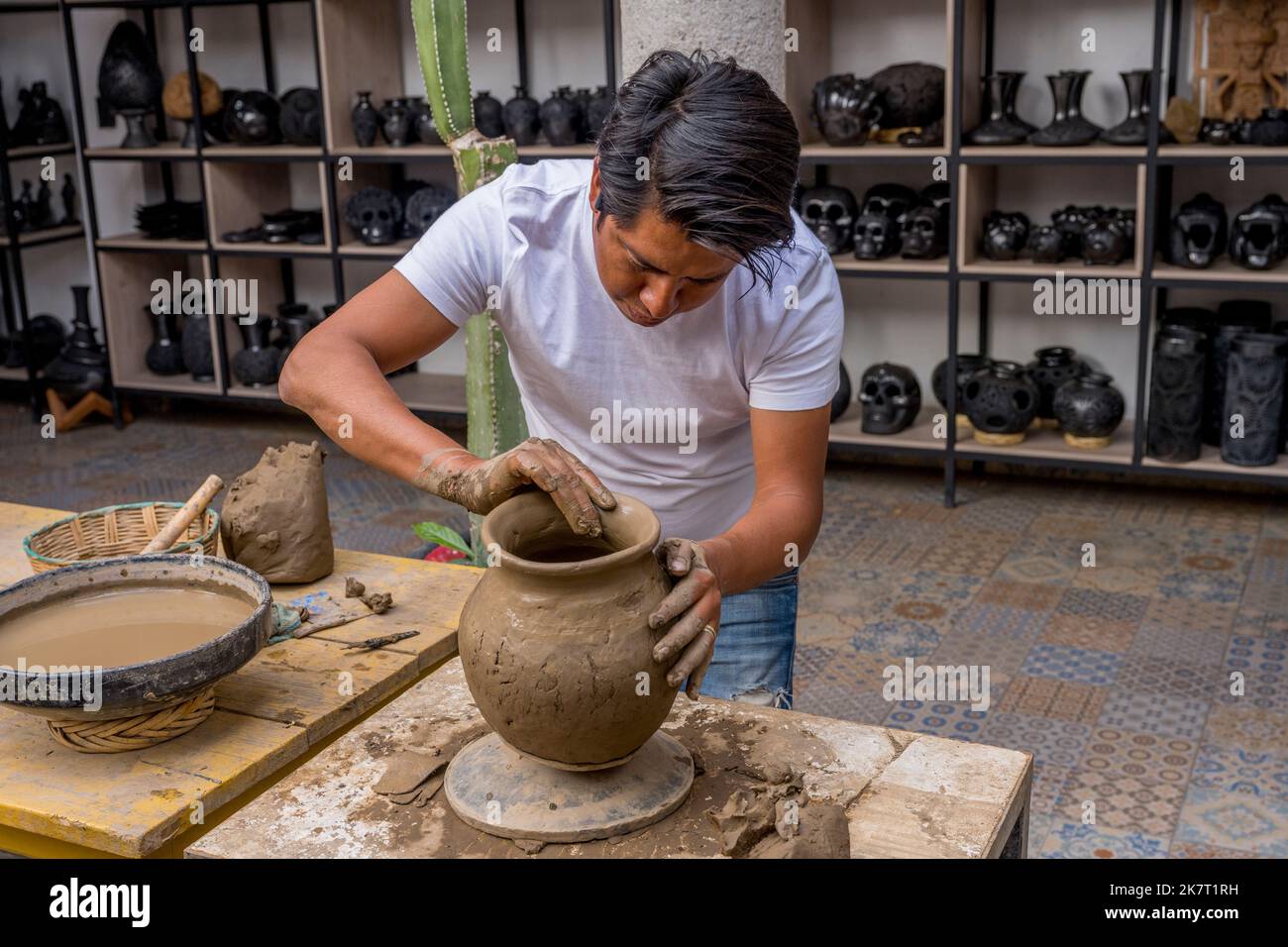A potter is making a Barro negro pottery (black clay pottery) vase ...